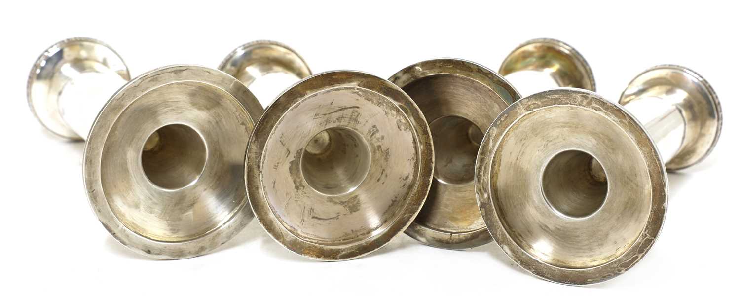 Lot 654 - A set of four silver candlesticks,